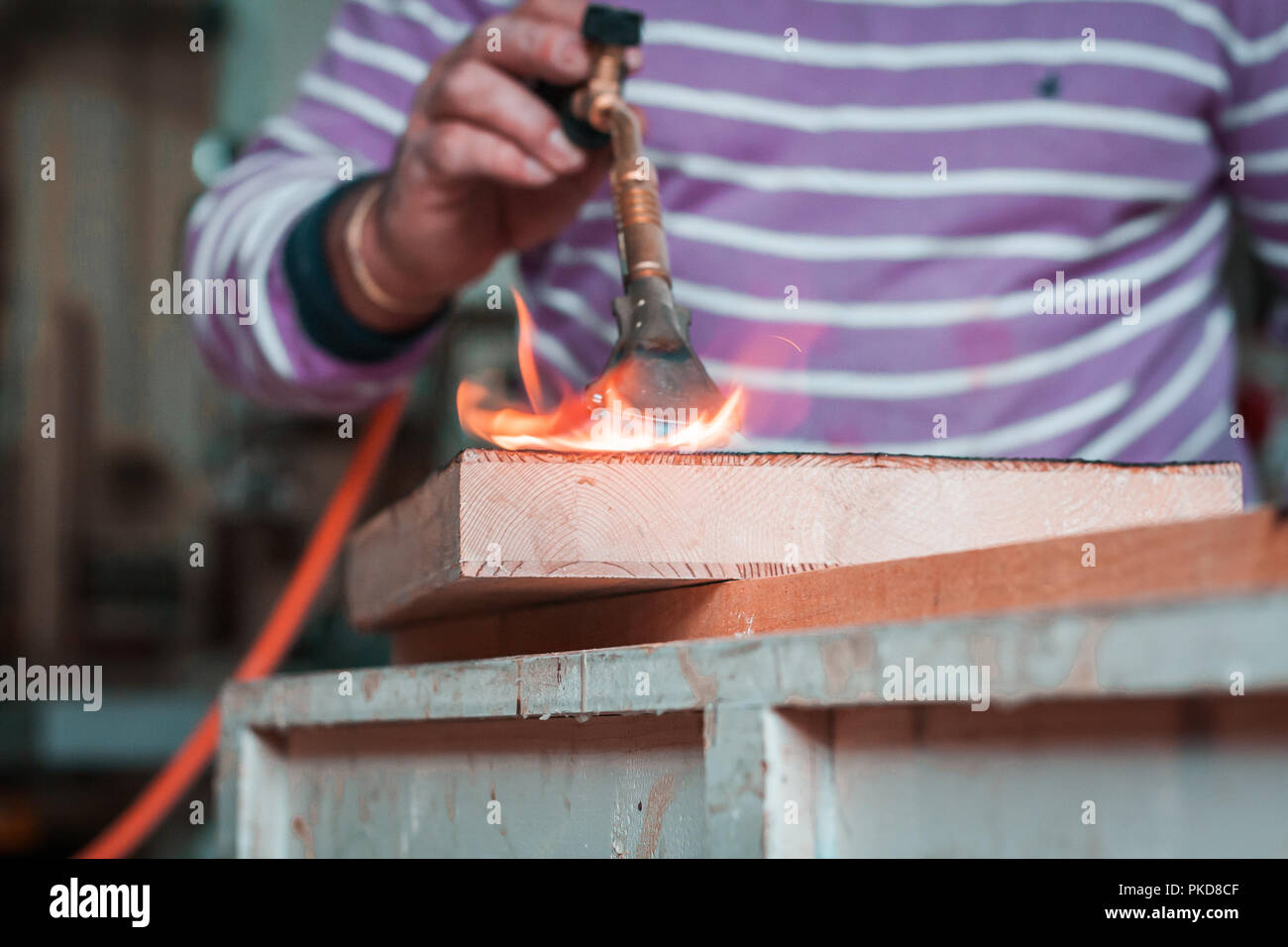 Burning wood planks in carpentry joint in Italy. Detail of gas burner ...