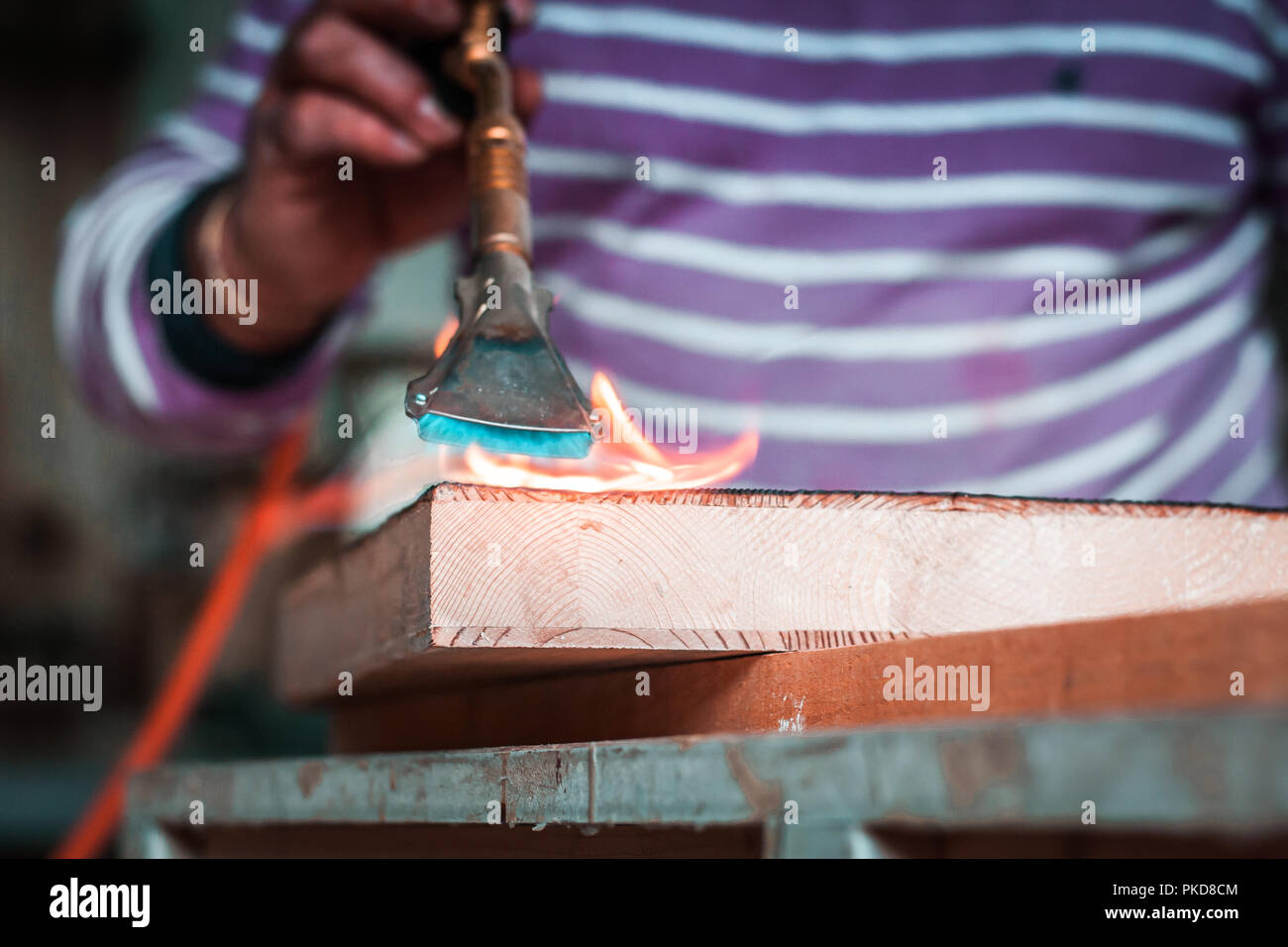 Burning wood planks in carpentry joint in Italy. Detail of gas burner ...