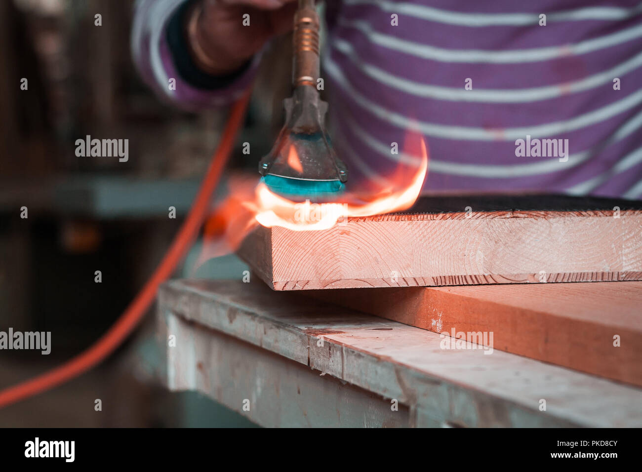 Burning wood planks in carpentry joint in Italy. Detail of gas burner ...