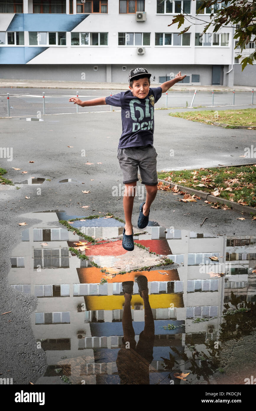 Boy jumps a street puddle Stock Photo - Alamy