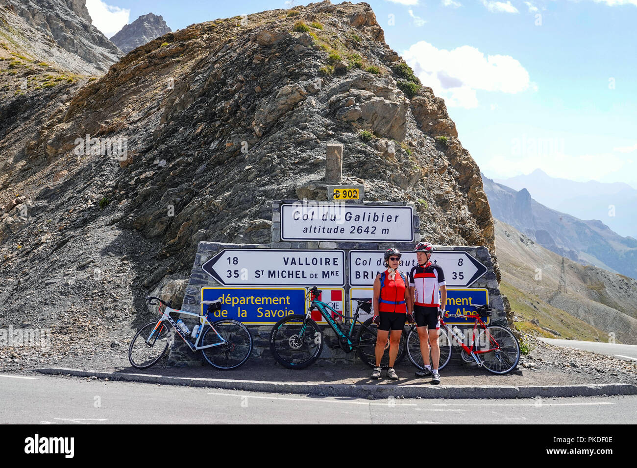 couple posing for photograph by sign, Col du Galibier, French Alps ...