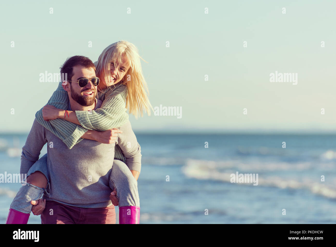 Men Giving Piggy Back Rides to his girlfriend At Sunset By The Sea ...