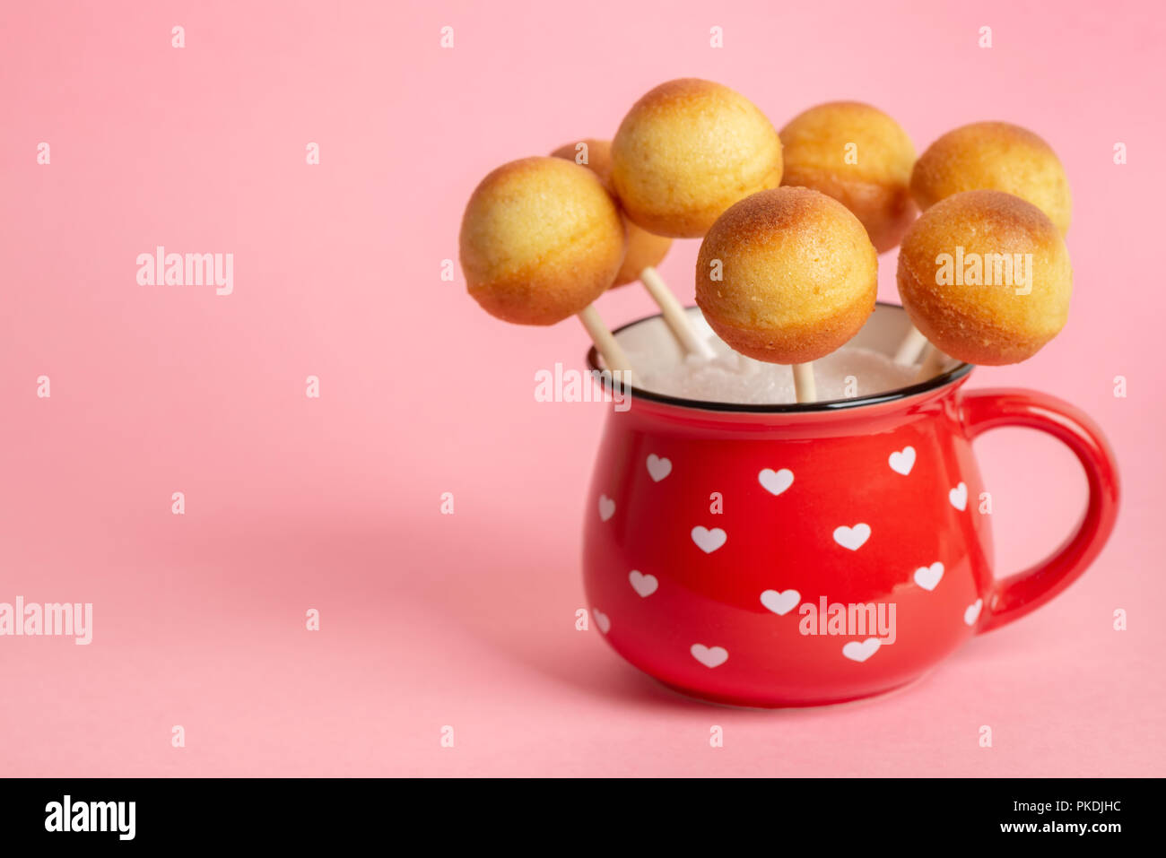 baked pop cakes in red jar with heart over pink background Stock Photo ...