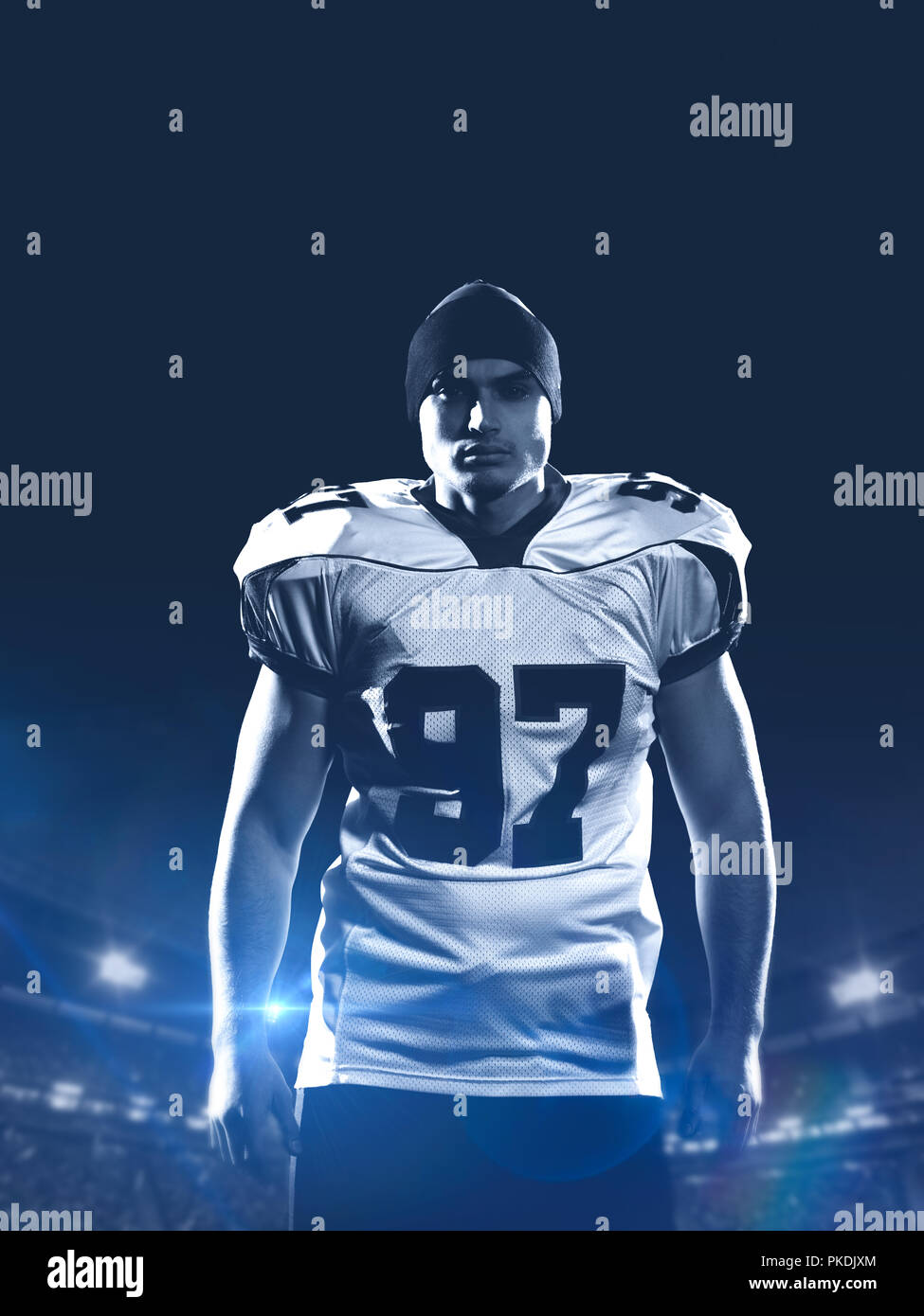 portrait of young confident American football player on field at night ...