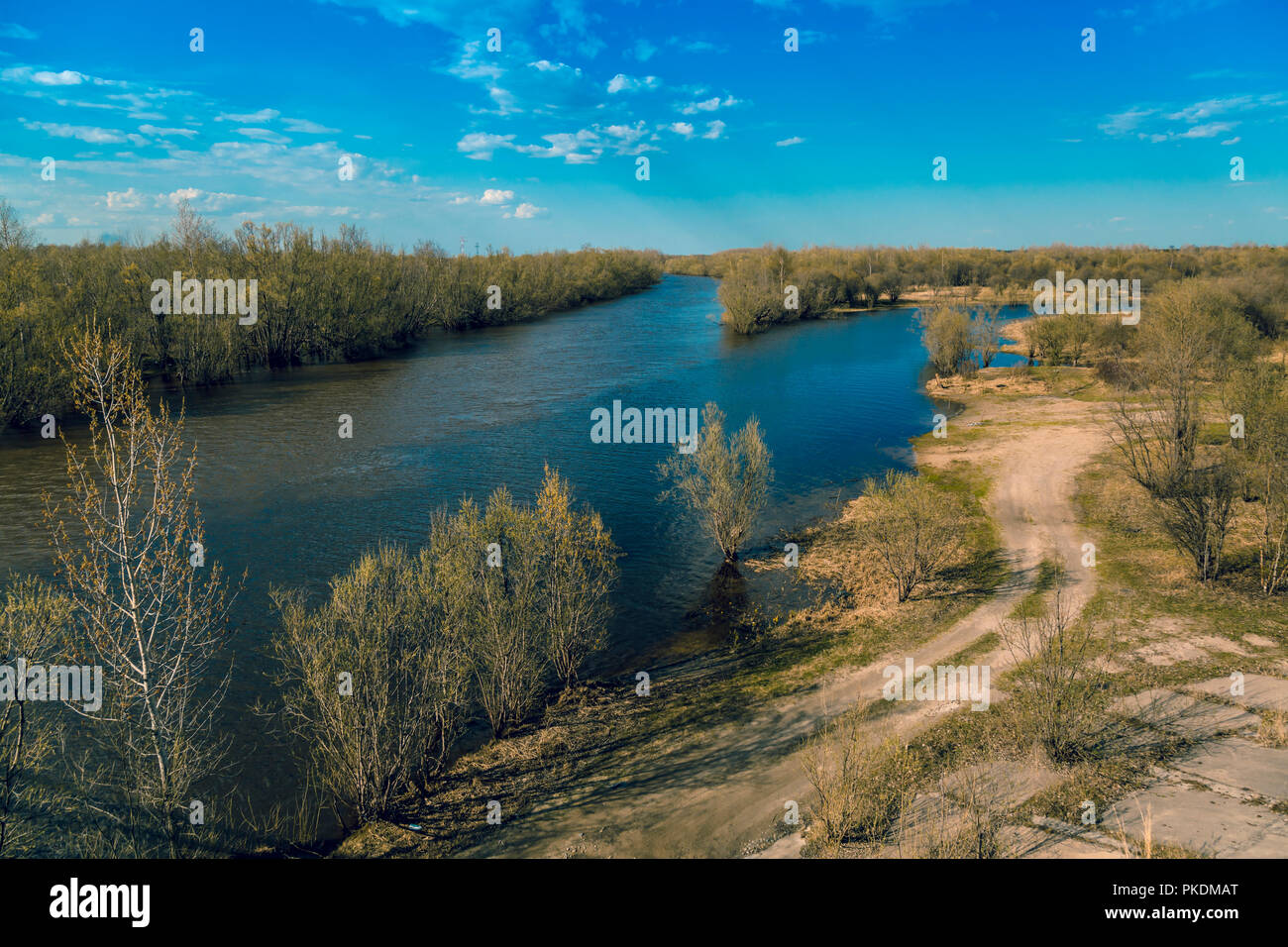 The Siberian river against a blue sky with clouds splits into two ...