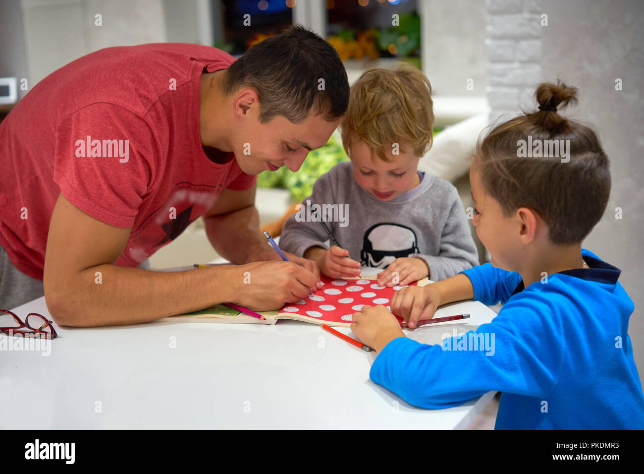 Father and two sons are painting using pencil and smiling while ...