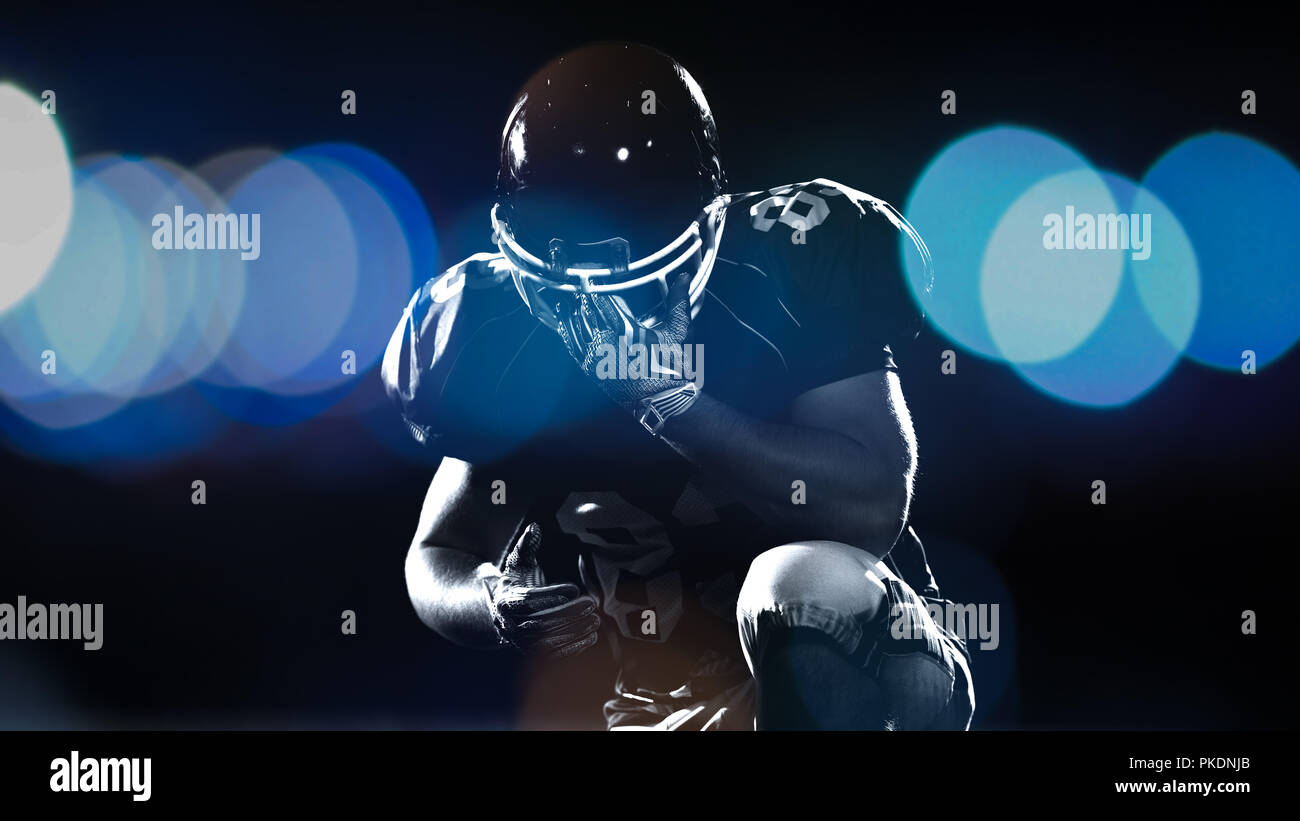portrait of young confident American football player on field at night ...