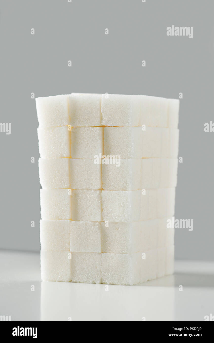 a pile of white sugar cubes, disposed in a block, on an off-white ...