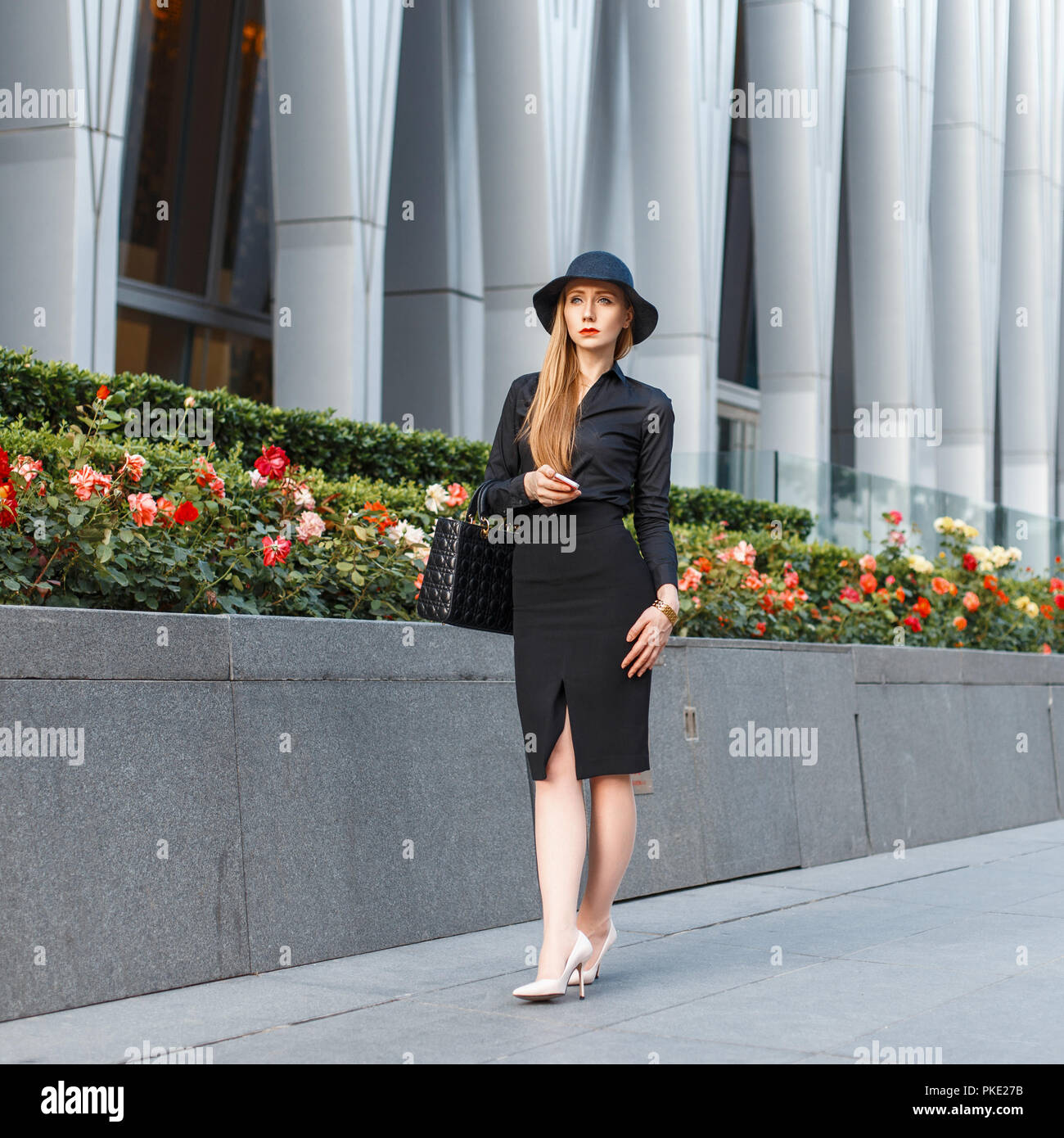 Beautiful elegant woman in a stylish hat in business style clothes on a ...
