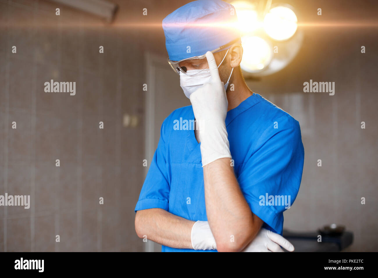 Doctor thinks in the operating room on the background of bright lights ...