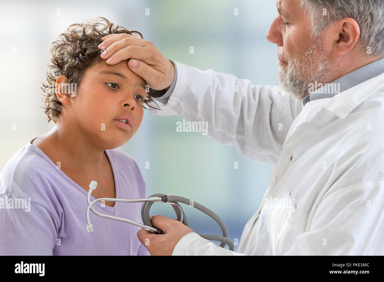 child fever. Male pediatrician checking teen boy head temperature with ...