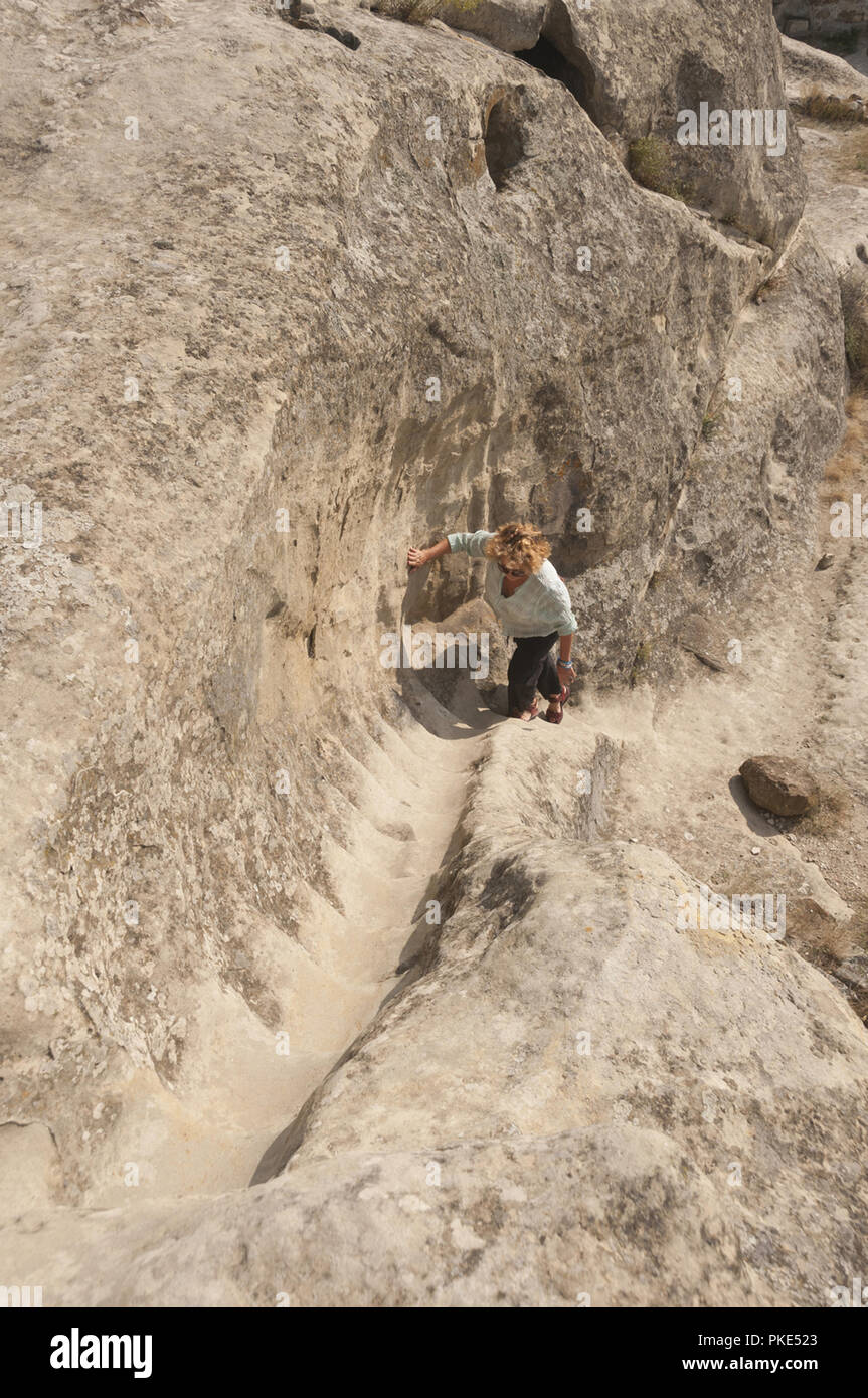 Georgia, Gori, woman ascending stone steps to Uplistsikhe cave city ...