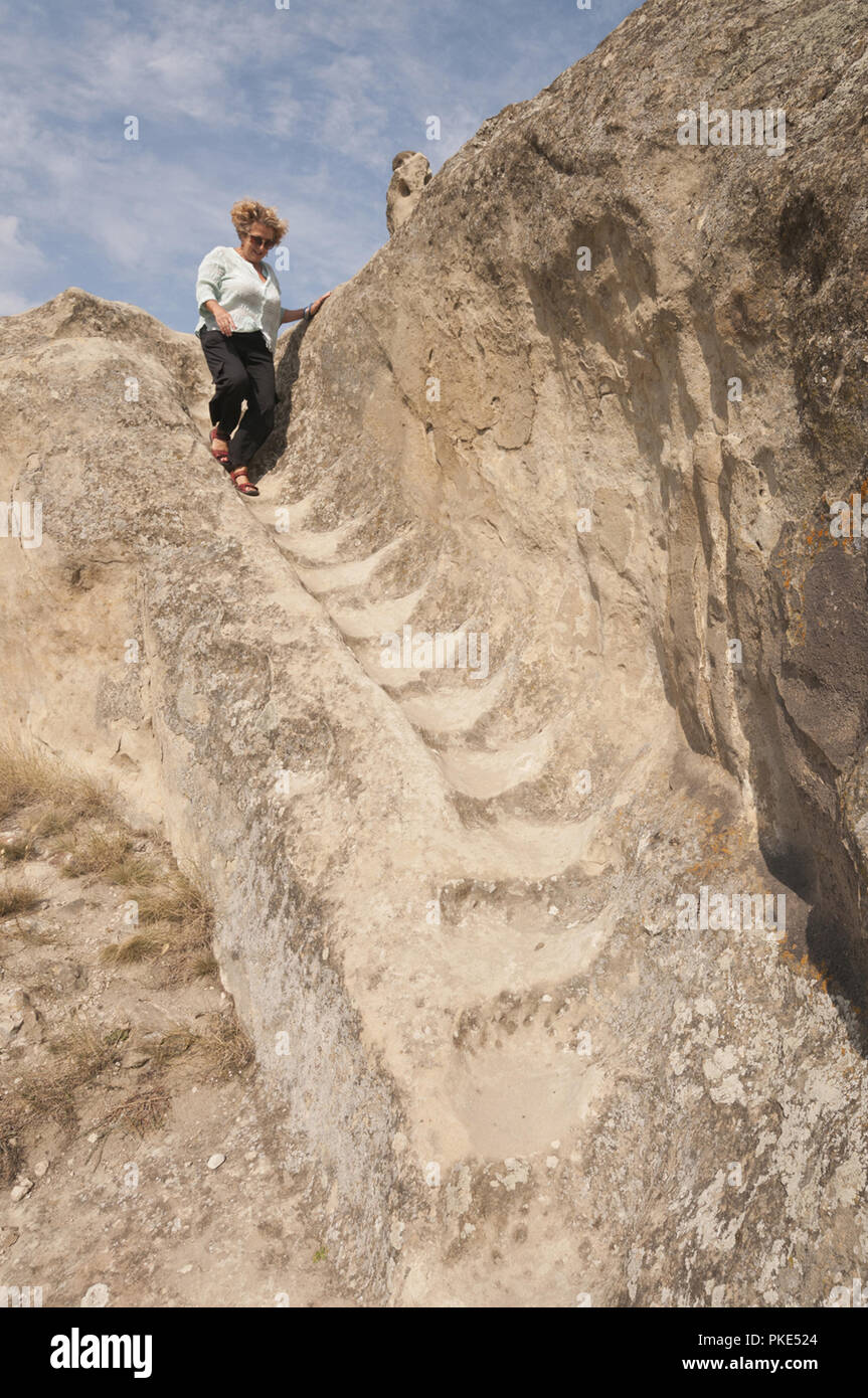 Georgia, Gori, woman descending stone steps to Uplistsikhe cave city ...