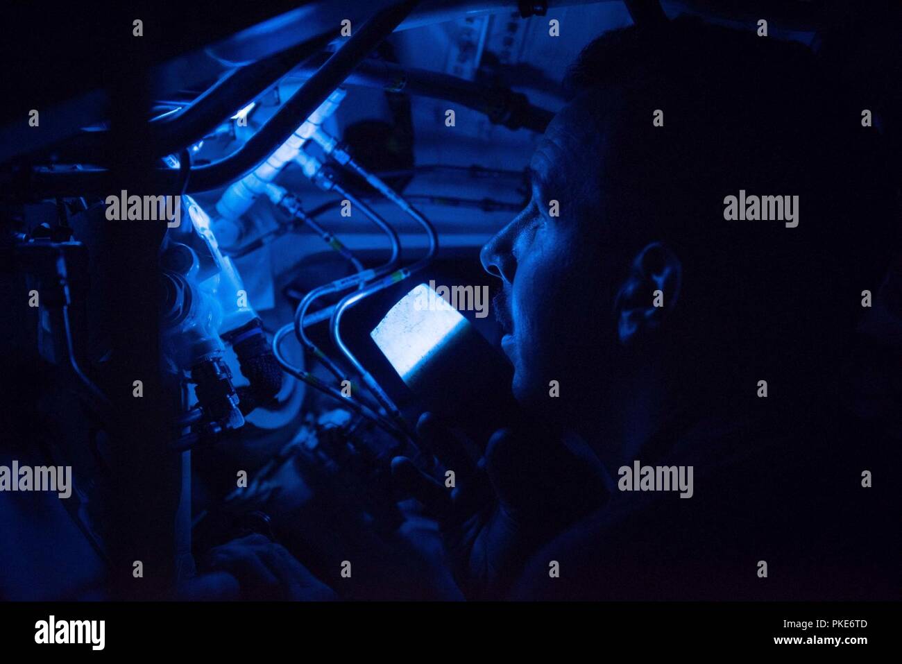 U.S. Navy Airman Alexander Mackenzie performs maintenance in the hangar ...