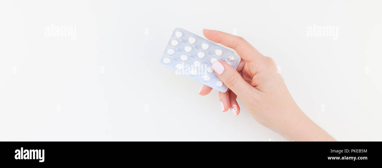 Woman hand with pastel manicure polish holding pills in blister ...