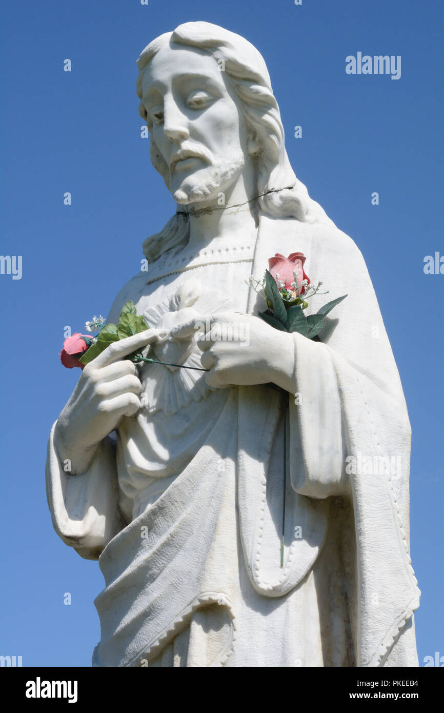 Gravestone detail of Jesus Christ holding all weather artificial red ...