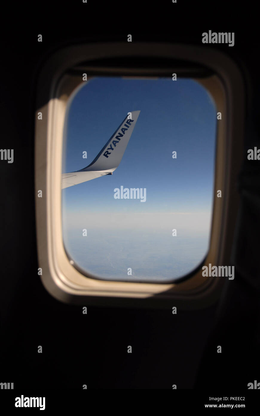 Porthole view out of a ryanair plane window in flight shows summer sky ...