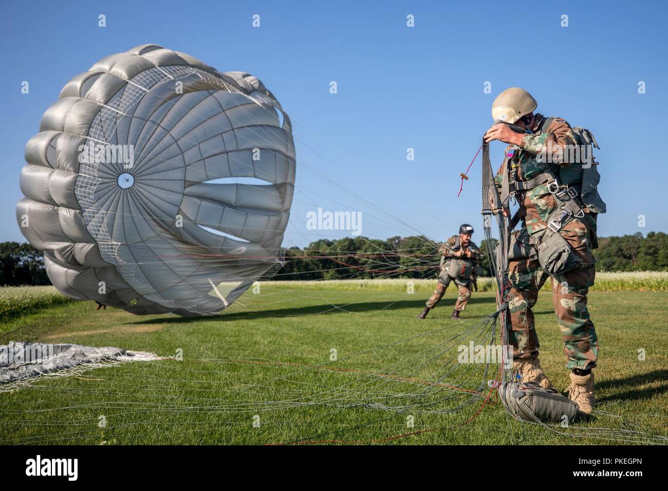 A South African paratrooper gathers his parachute as another ...