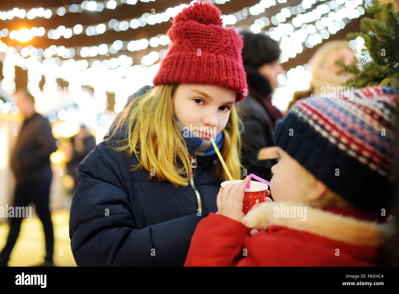 Two adorable sisters drinking hot chocolate on traditional Christmas ...