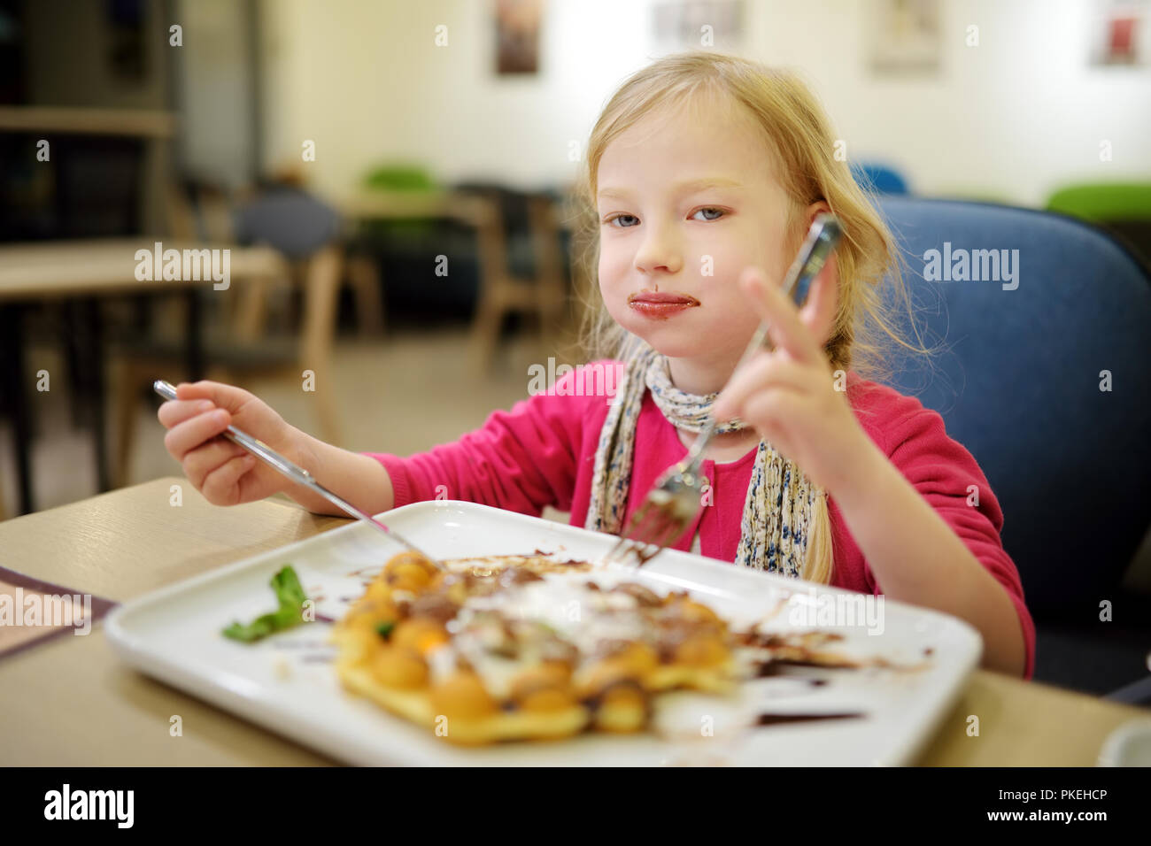 Adorable little girl eating bubble waffle with fruits, chocolate and ...