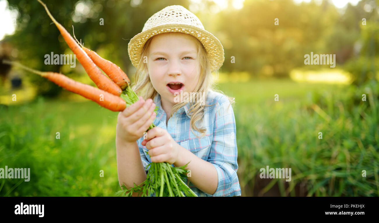 Cute little girl wearing straw hat holding a bunch of fresh organic ...