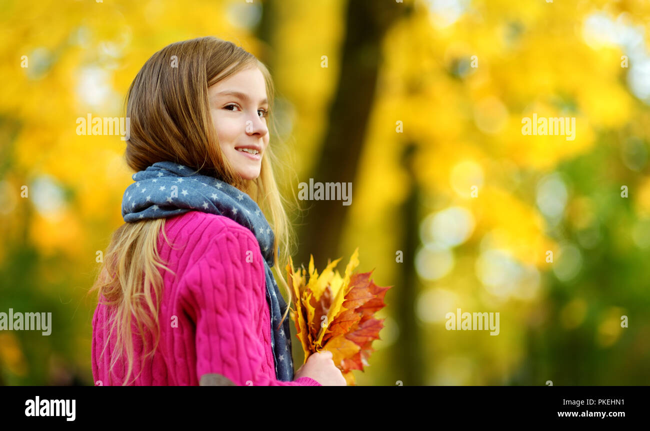 Cute little girl having fun on beautiful autumn day. Happy child playing in autumn park. Kid ...
