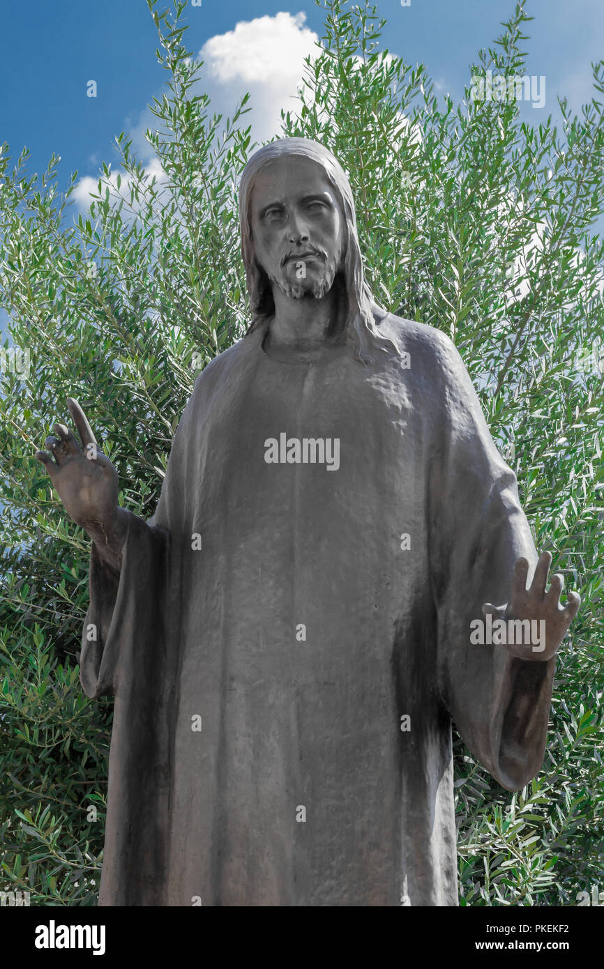 Old bronze Jesus Christ statue in a old cemetery with olive tree in the ...