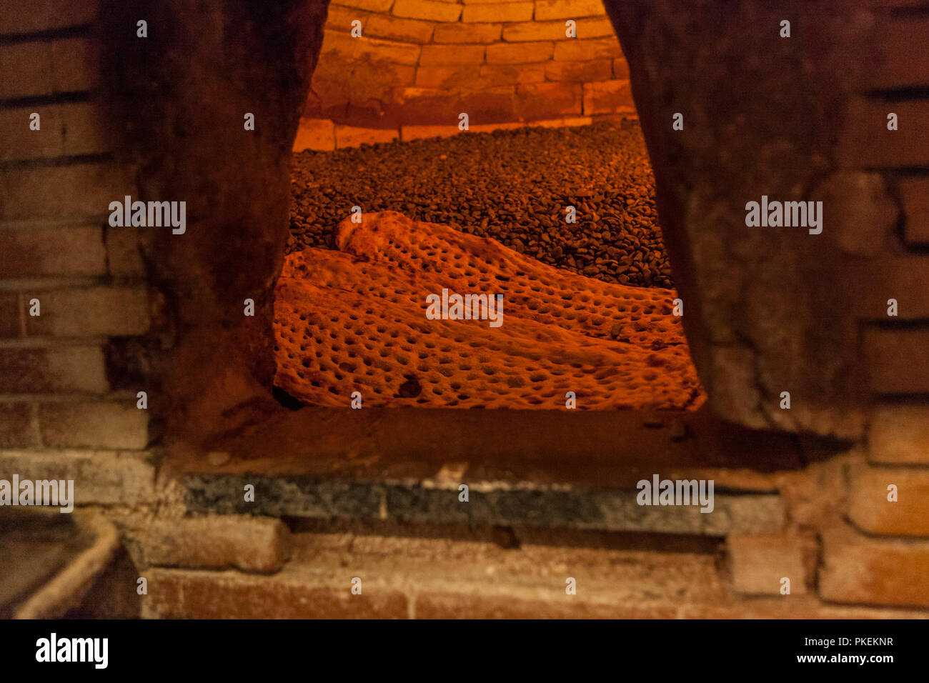 Sangak, a leavened Iranian flatbread, being baked on small stones in a ...