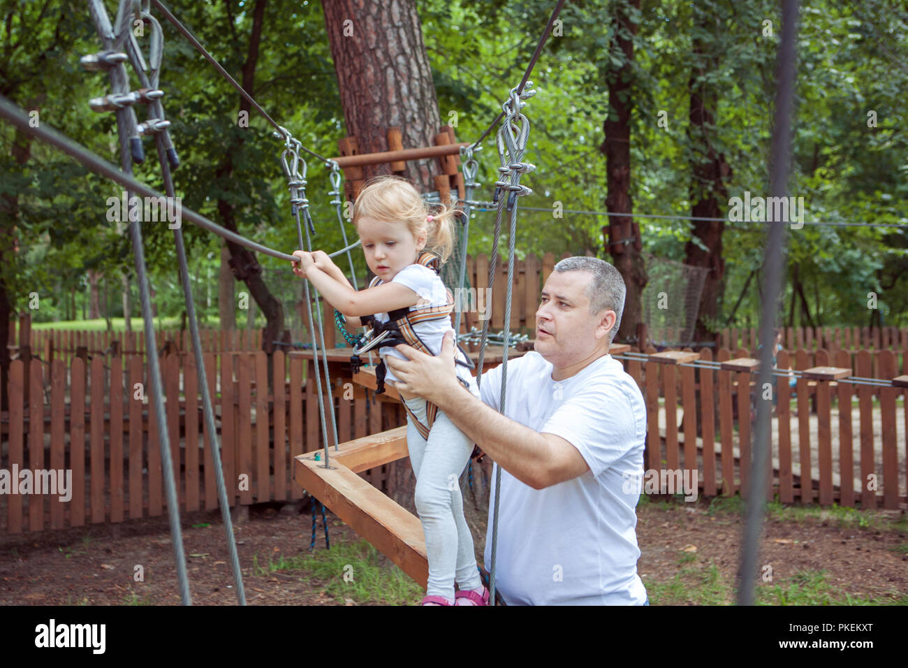 Father helps his daughter in a rope park Stock Photo - Alamy