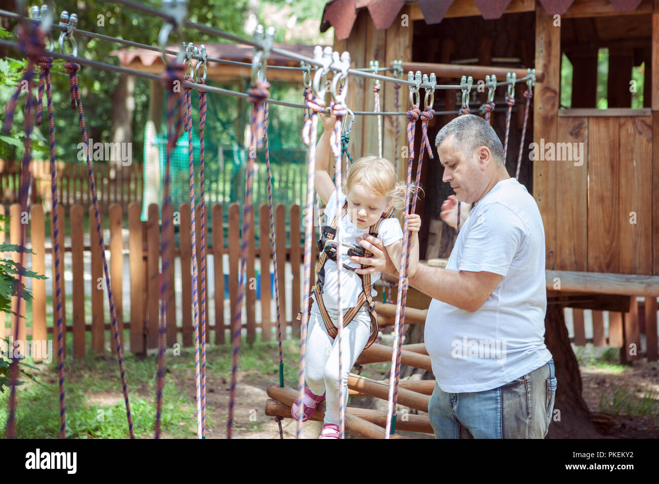 Young father helping his little daughter in the rope park Stock Photo ...