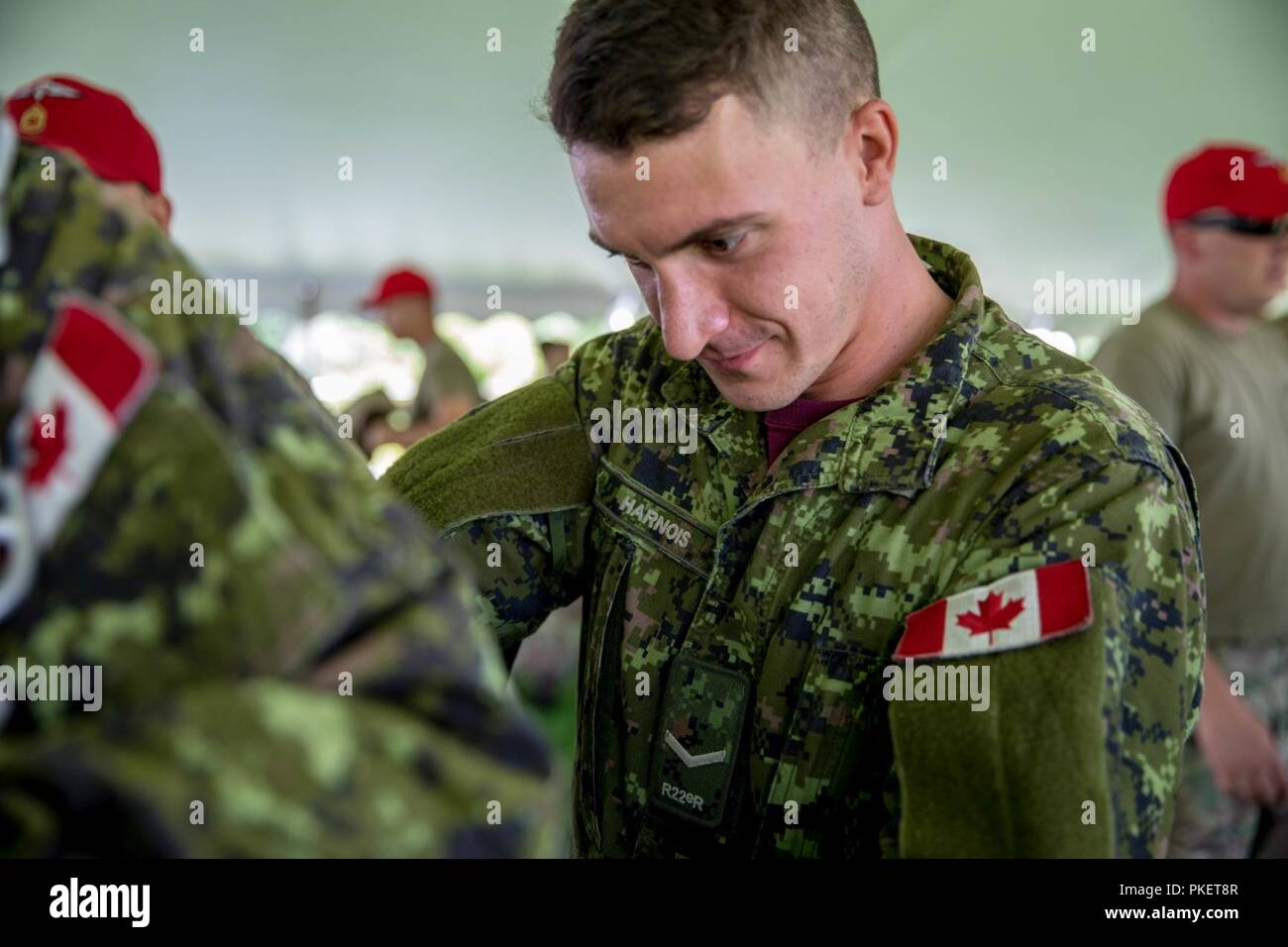 Canadian paratrooper Pte. Alex Harnois assists another paratrooper with ...