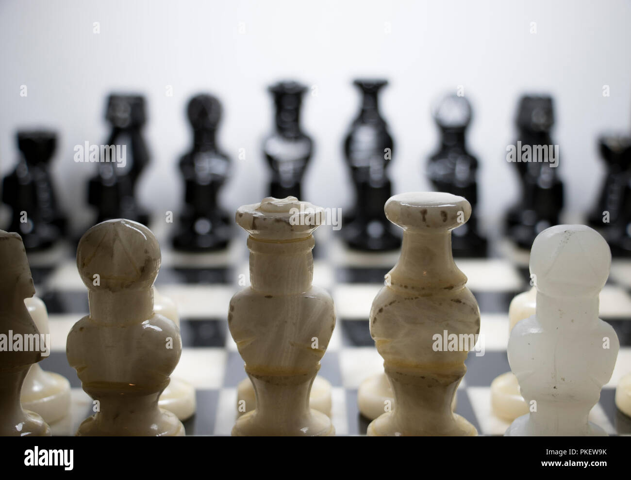White chess pieces facing black chess pieces out of focus. Team concept ...