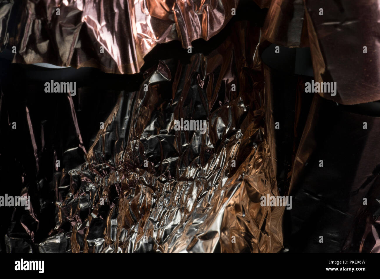 Rough texture of bent and wrinkled metal foil reflecting on a black ...