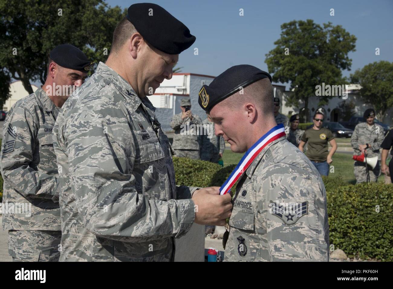 U.S. Air Force Col. Thomas Miner, Security Forces Group commander, places a medal around the ...