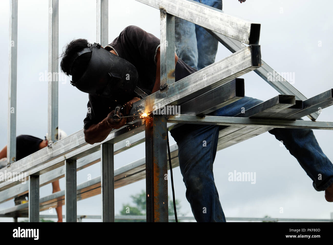 Asian man welder climb on steel frame and welding to build steel house ...