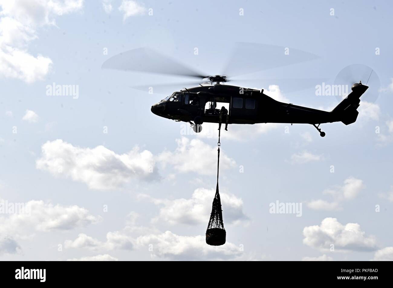 A UH-60 Blackhawk helicopter carries a load from a cargo pick-up site ...
