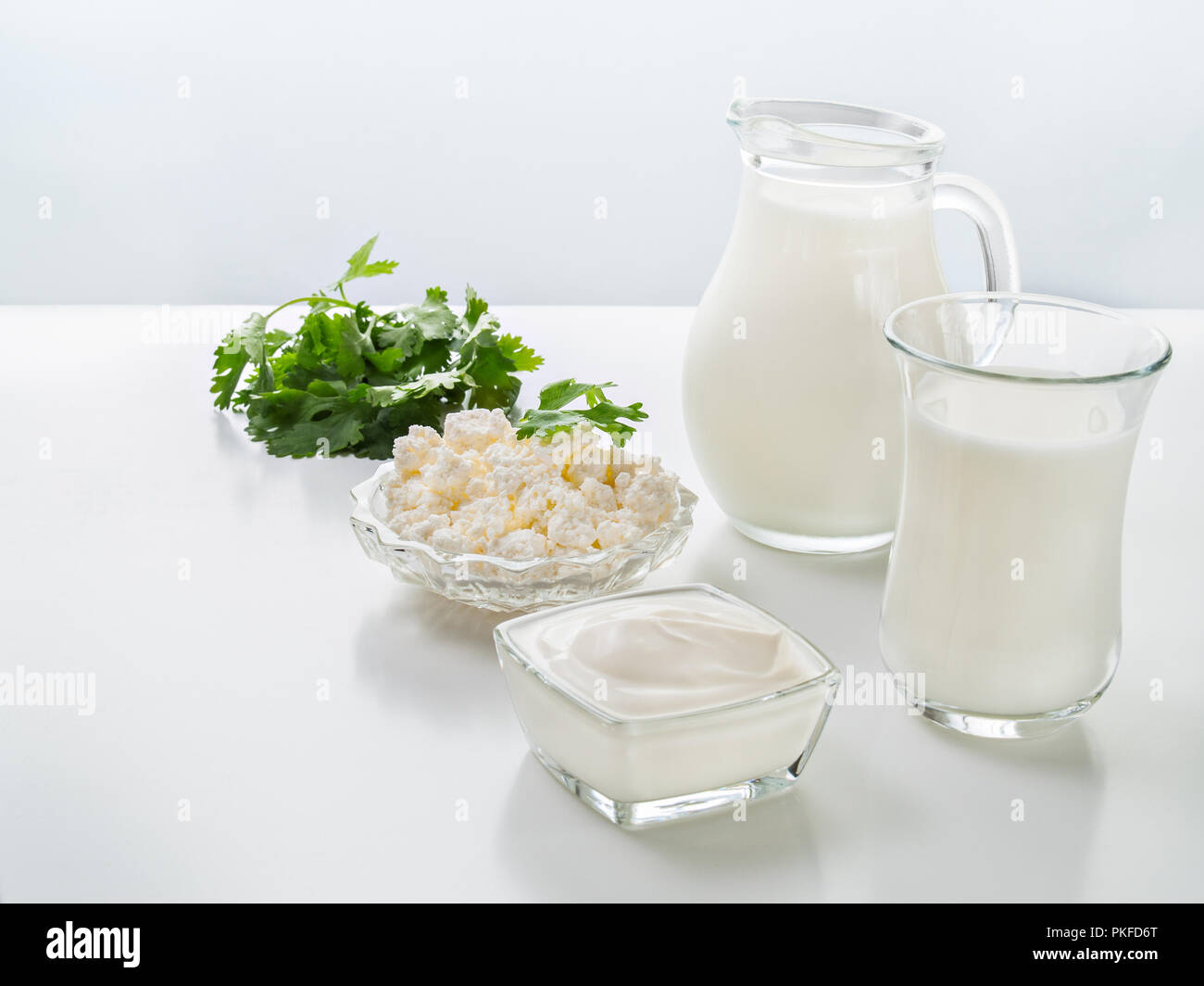 Milk in a jug, milk in a mug, sour cream in a plate, cottage cheese in ...
