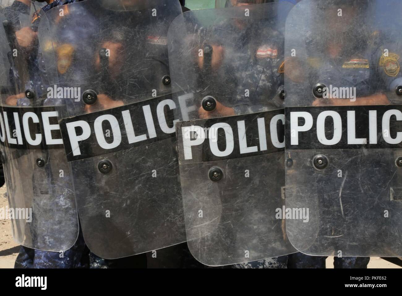 Iraqi Federal Police members stand behind their shields during riot ...