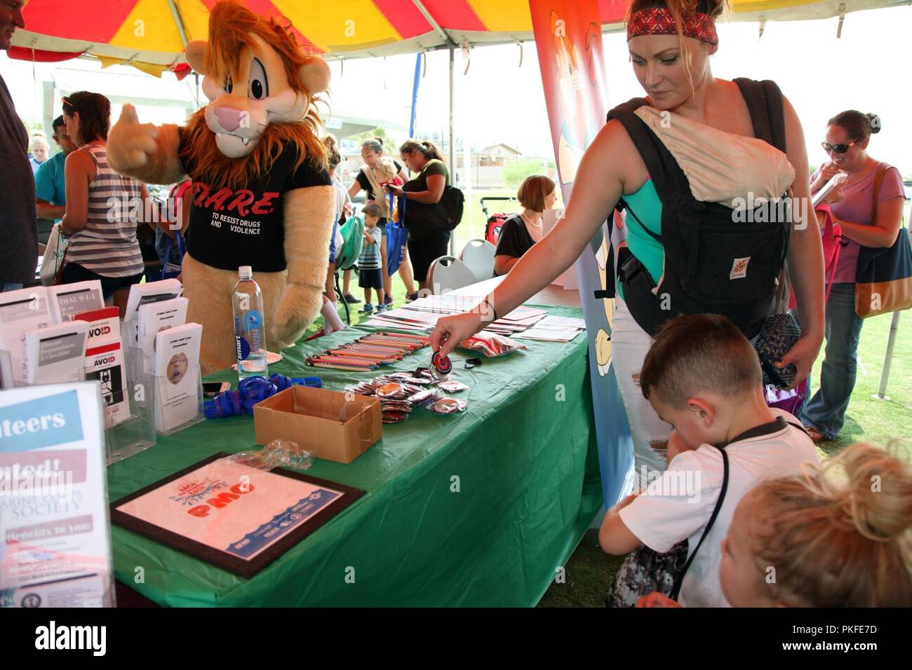 Daren the DARE Lion looks on while family members peruse items at the ...