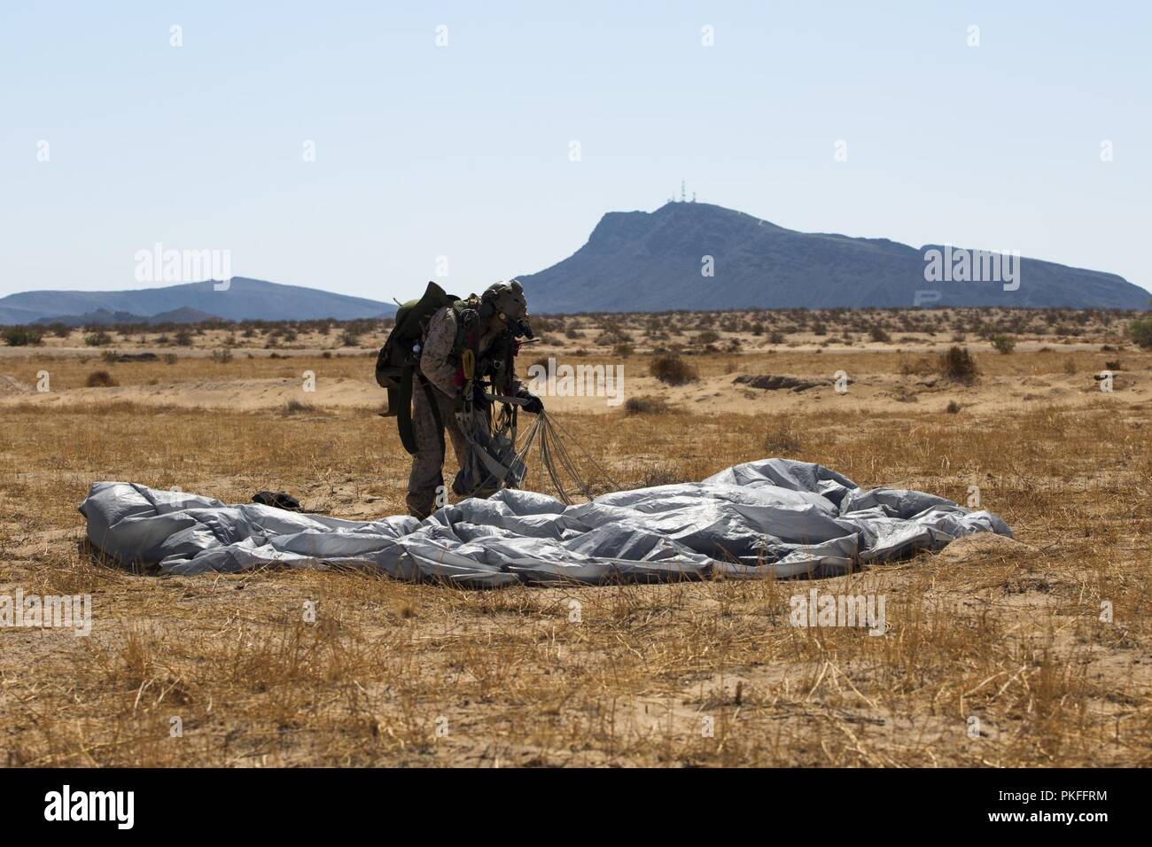 A Reconnaissance Marine packs his parachute after parachute jumps ...