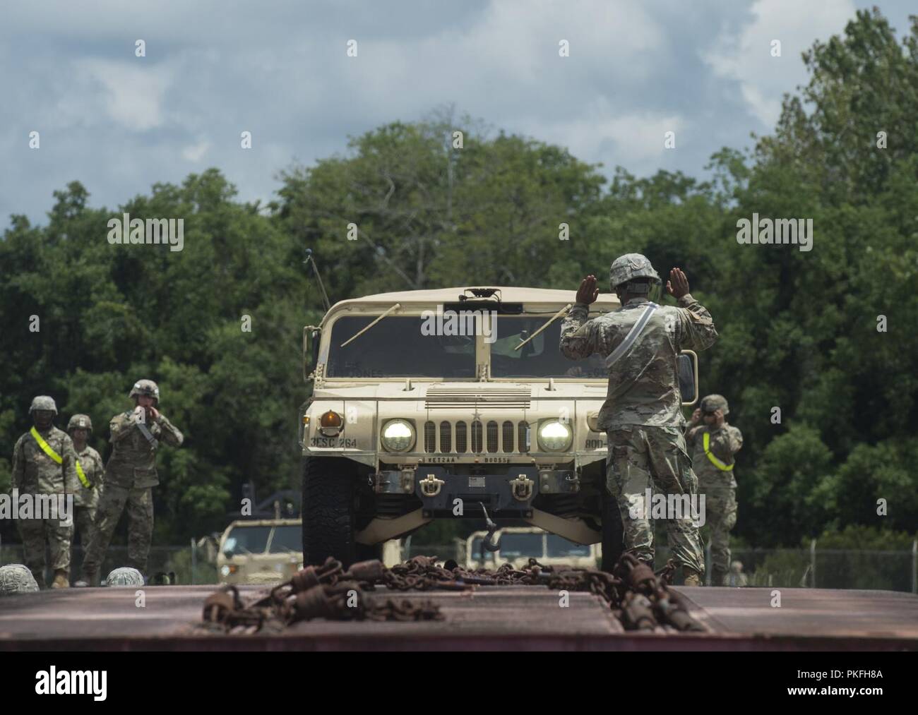 U.S. Army Soldiers guides a Humvee driver during rail operations as ...