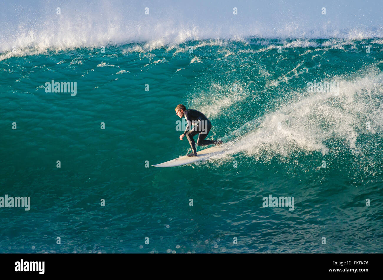 A surfer expertly rides a large green wave, balancing gracefully ...