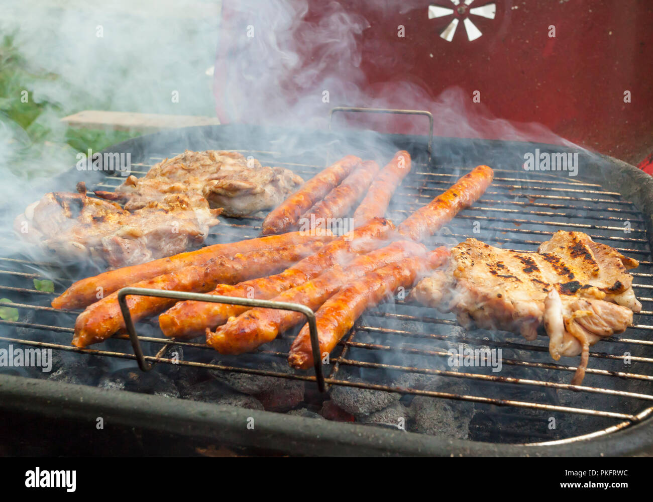 Variety of meat on an outdoor, sunlit, smoking barbecue grill Stock ...
