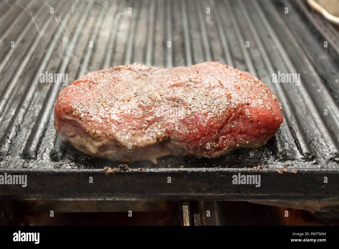 Sizzling raw beef steak on a grill Stock Photo - Alamy