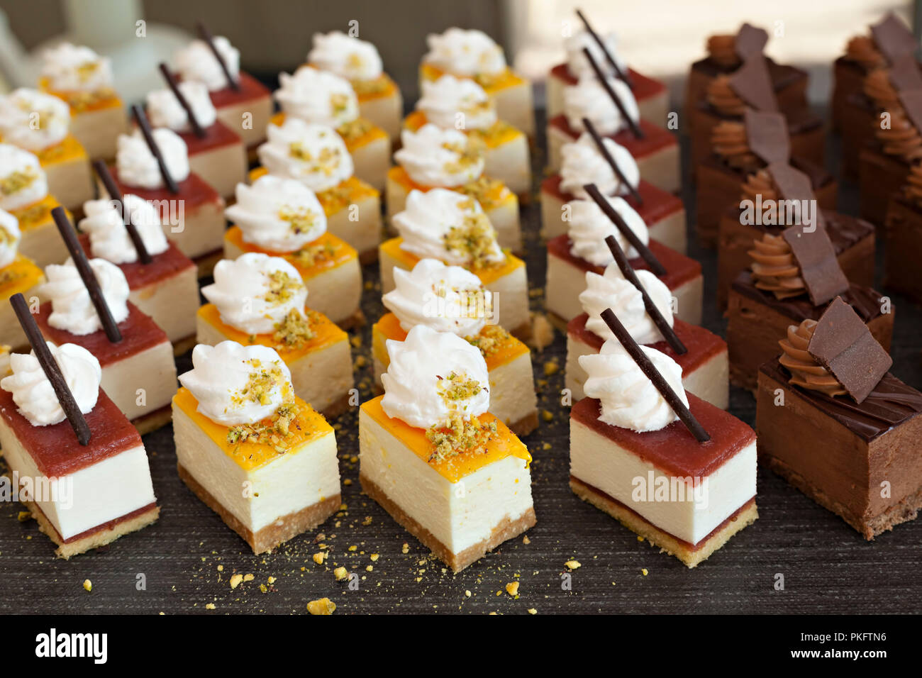 Small chocolate and vanilla layered cakes in rows on candy buffet ...