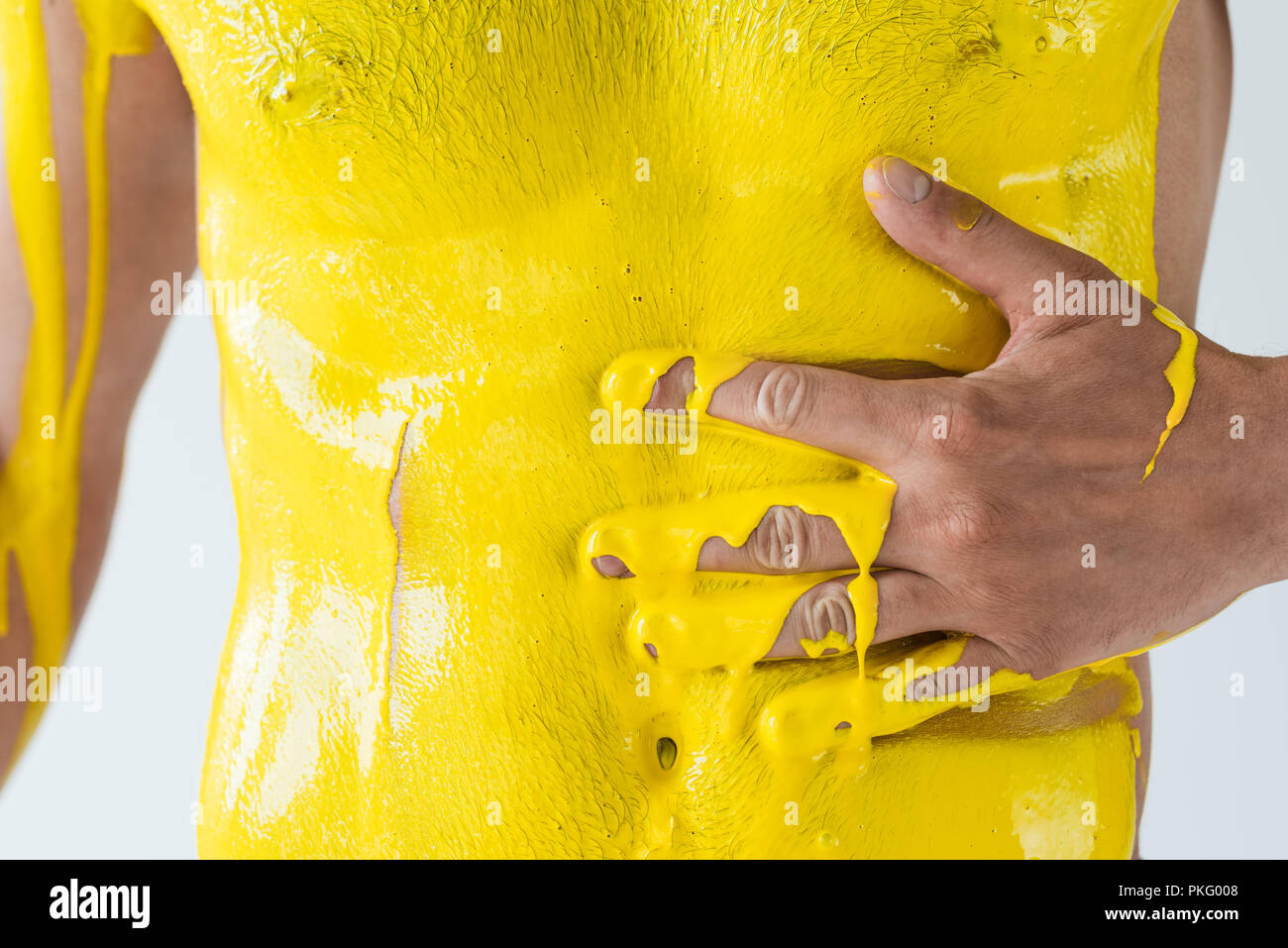 Cropped view of male body covered with yellow paint isolated on white ...