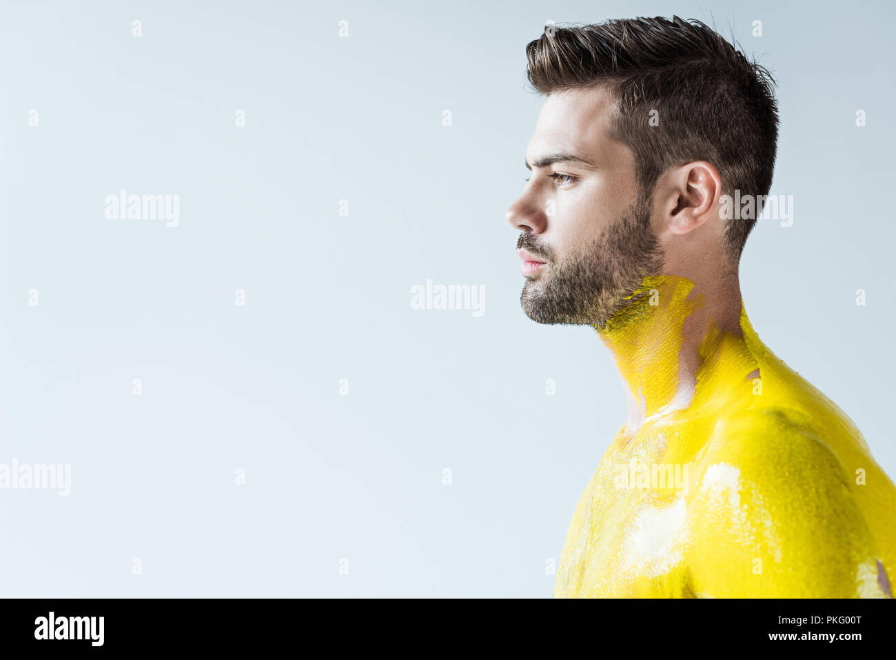 Young man with body painted in yellow isolated on white background ...