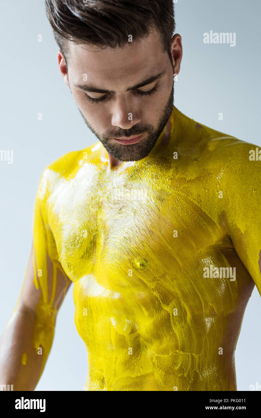 Man looking at his body painted yellow isolated on white background ...