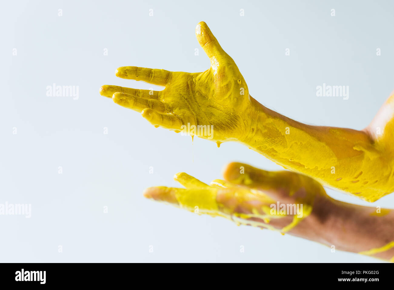 Cropped view of male hands covered with yellow paint isolated on white ...