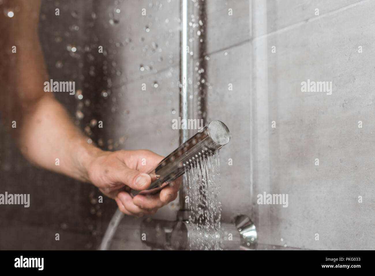 Cropped view of male hand holding shower behind glass Stock Photo - Alamy